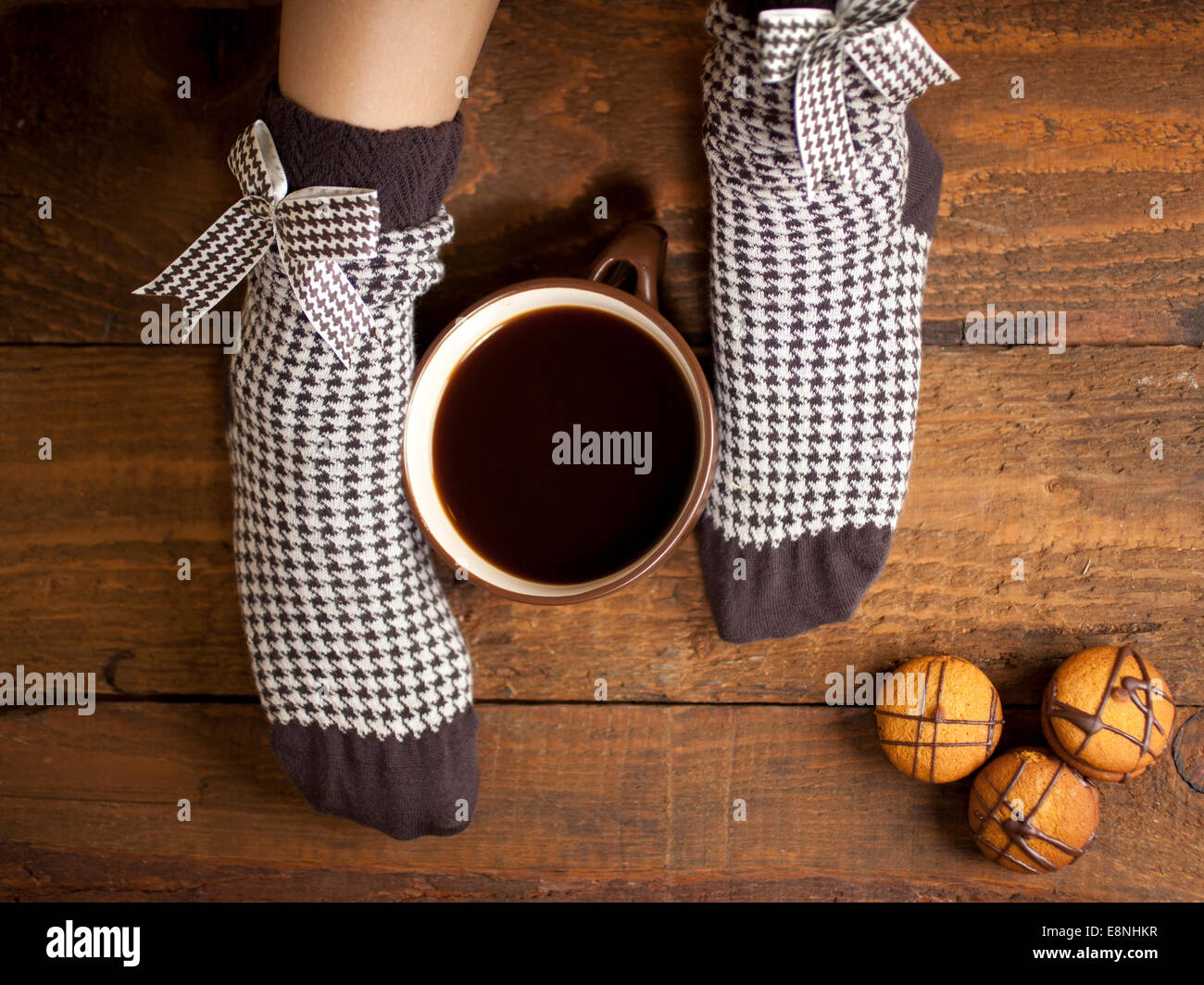 A cup of coffee or hot chocolate and female feet with sweet brown socks ...