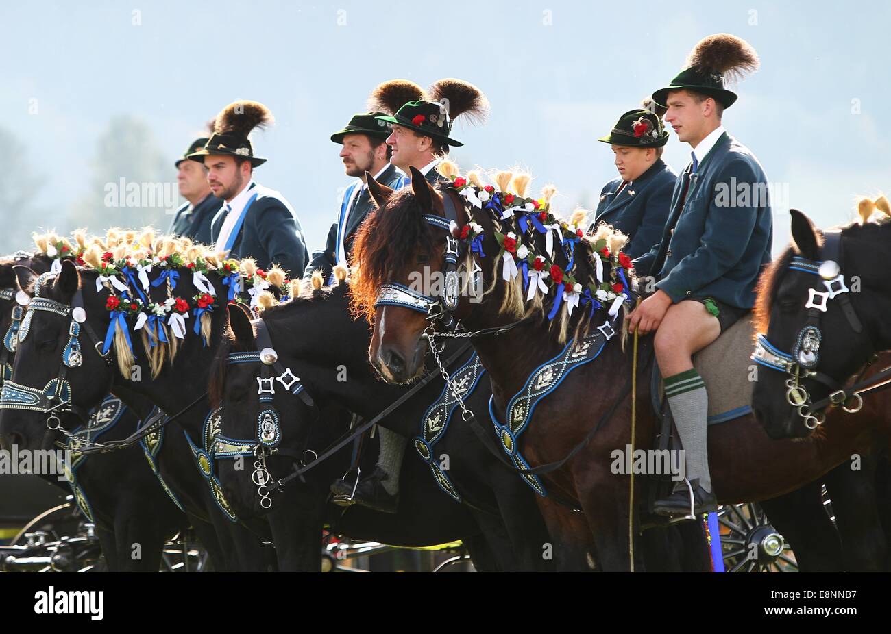 Riders in traditional attire sit on festively decorated horses in front ...