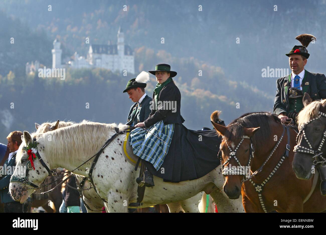 Female and male riders in traditional attire sit on festively decorated ...
