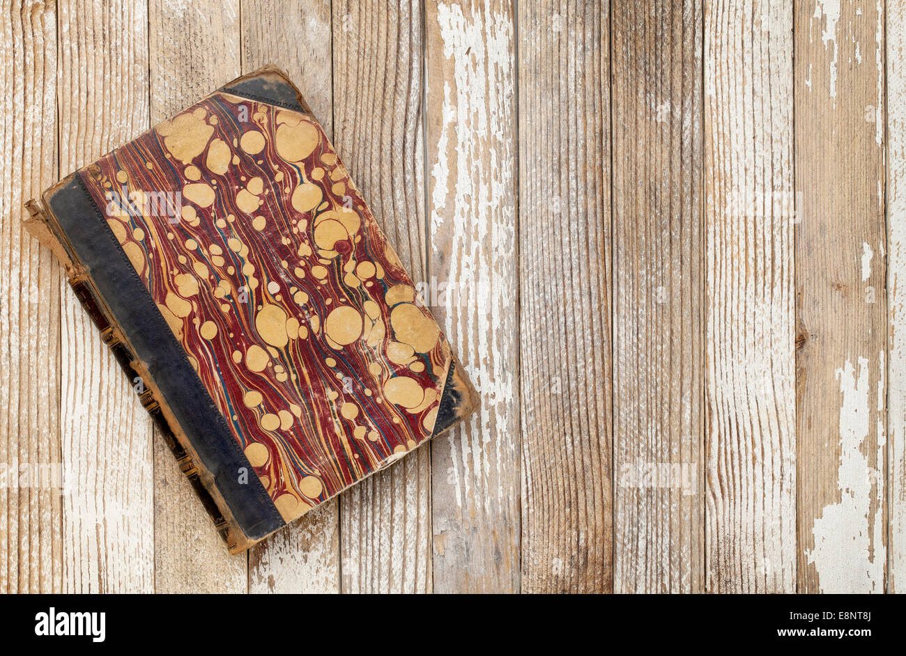 worn out antique book in marbled paper cover a grunge wood background ...