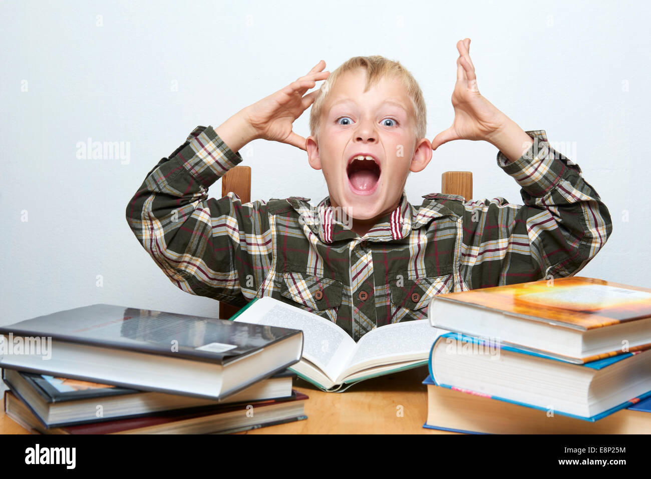 Little child blond focused student boy sitting at desk and reading book ...