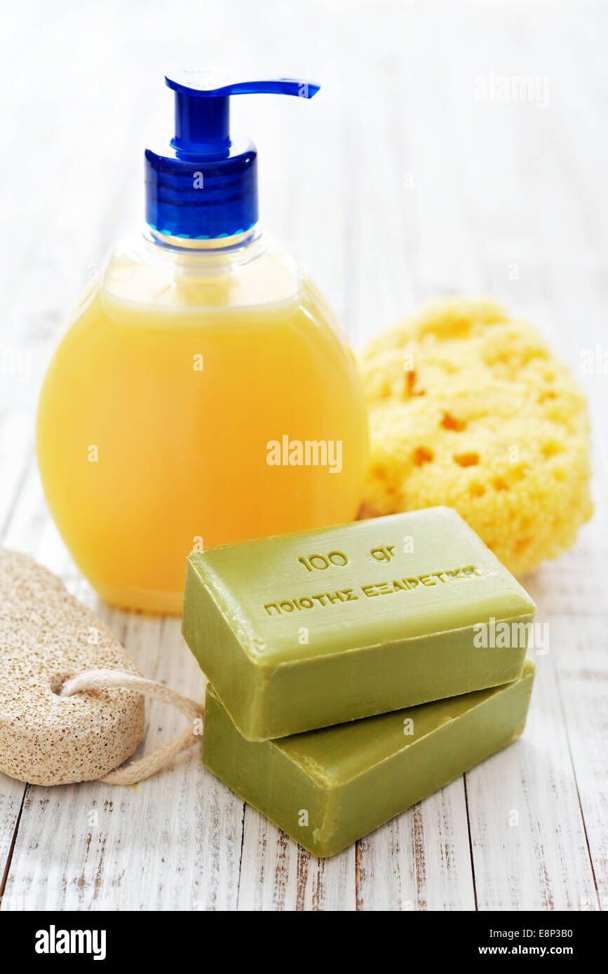 Greek olive soap with shower gel and bath sponge on wooden background ...