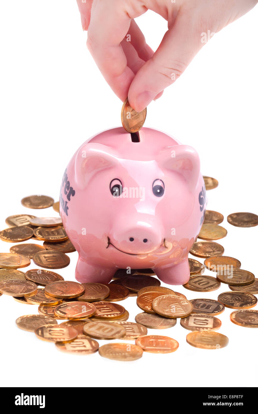 Saving coins in pig-shaped money-box Stock Photo - Alamy