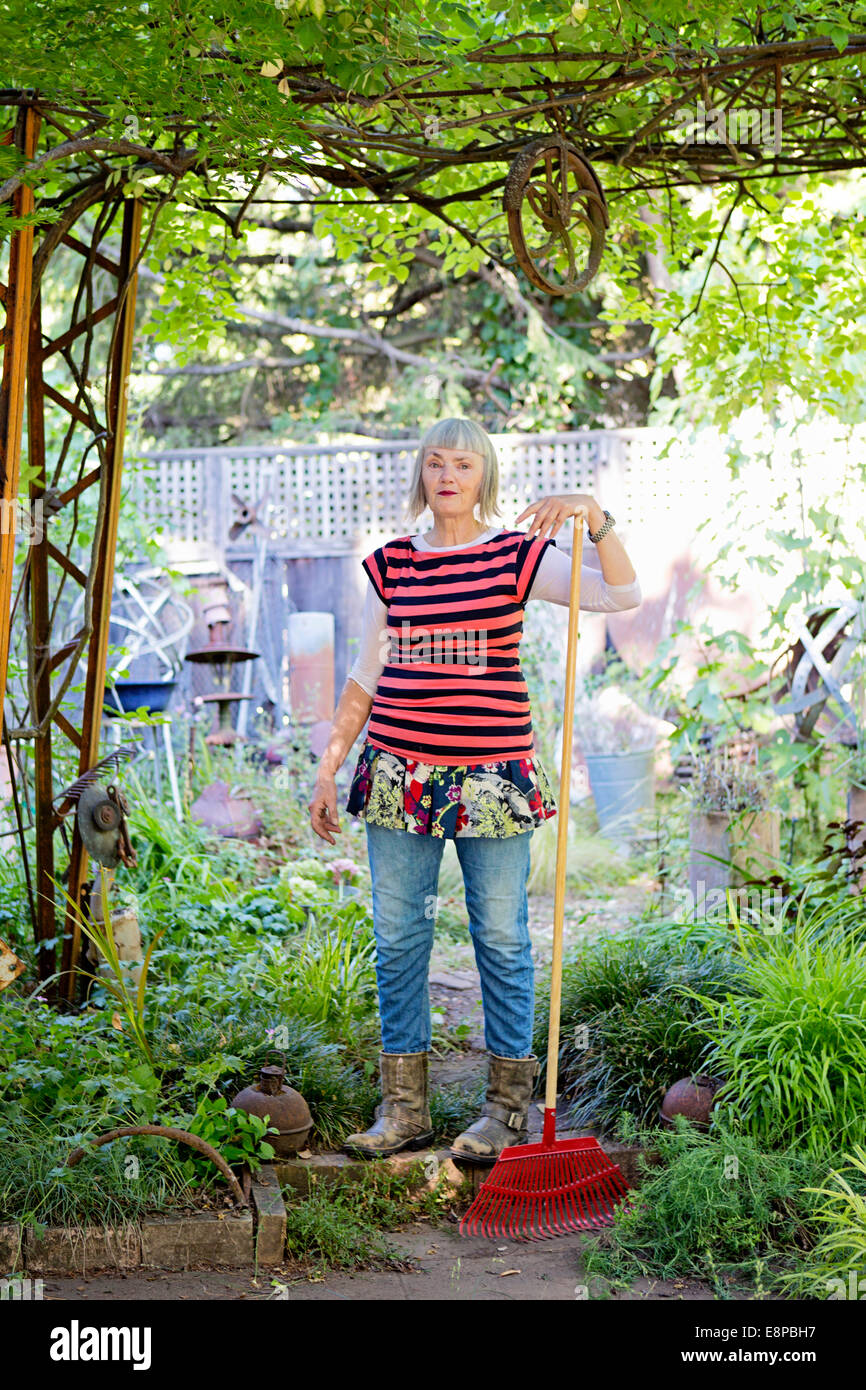 Senior woman in garden with rake Stock Photo - Alamy