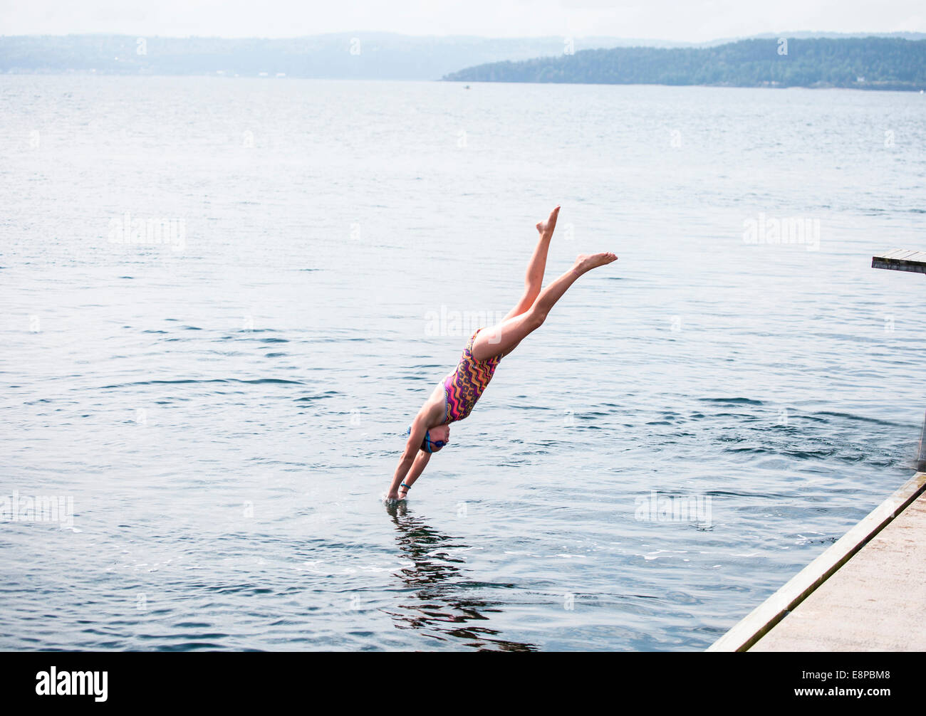Woman jumping into sea from pier Stock Photo - Alamy