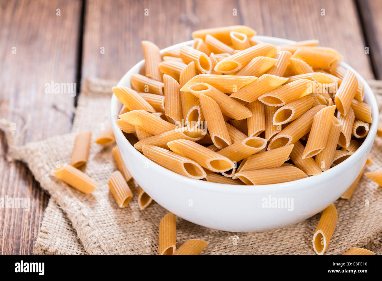Wholemeal Pasta (Penne) as close-up shot on vintage wooden background ...