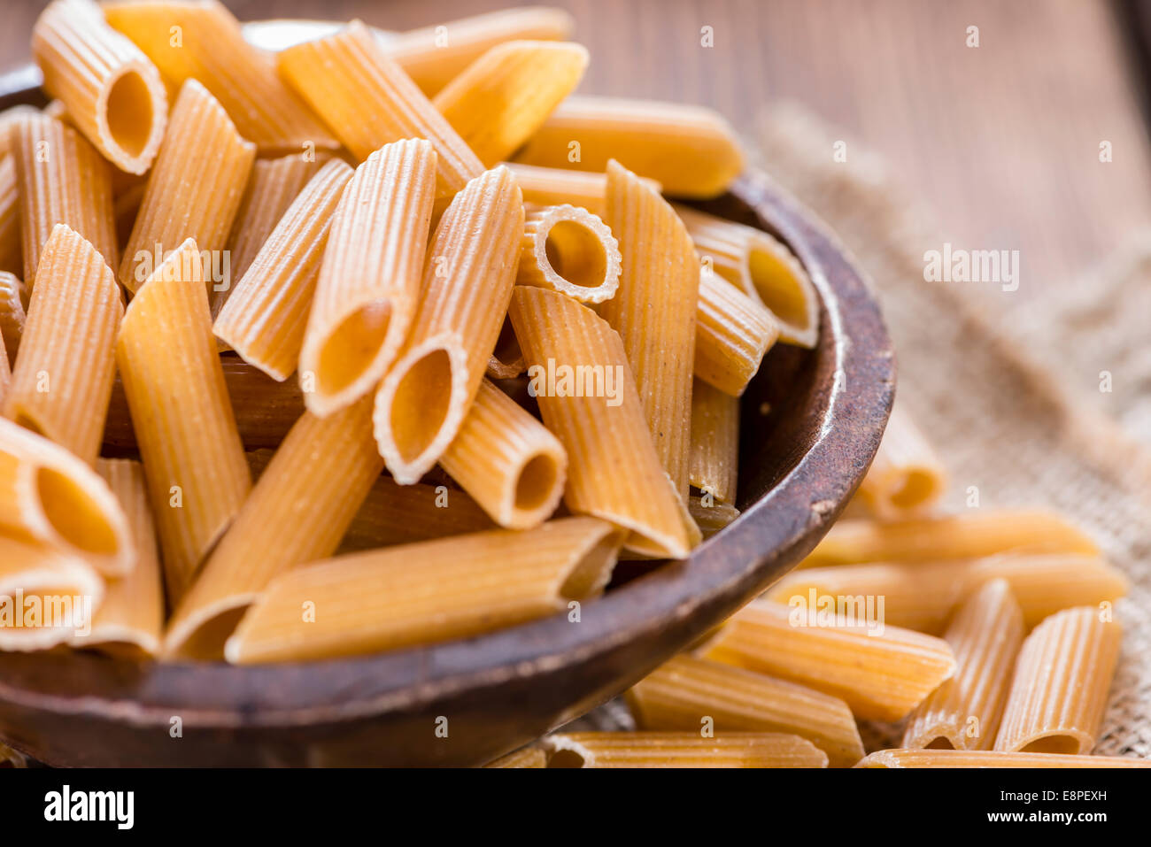 Wholemeal Pasta (Penne) as close-up shot on vintage wooden background ...