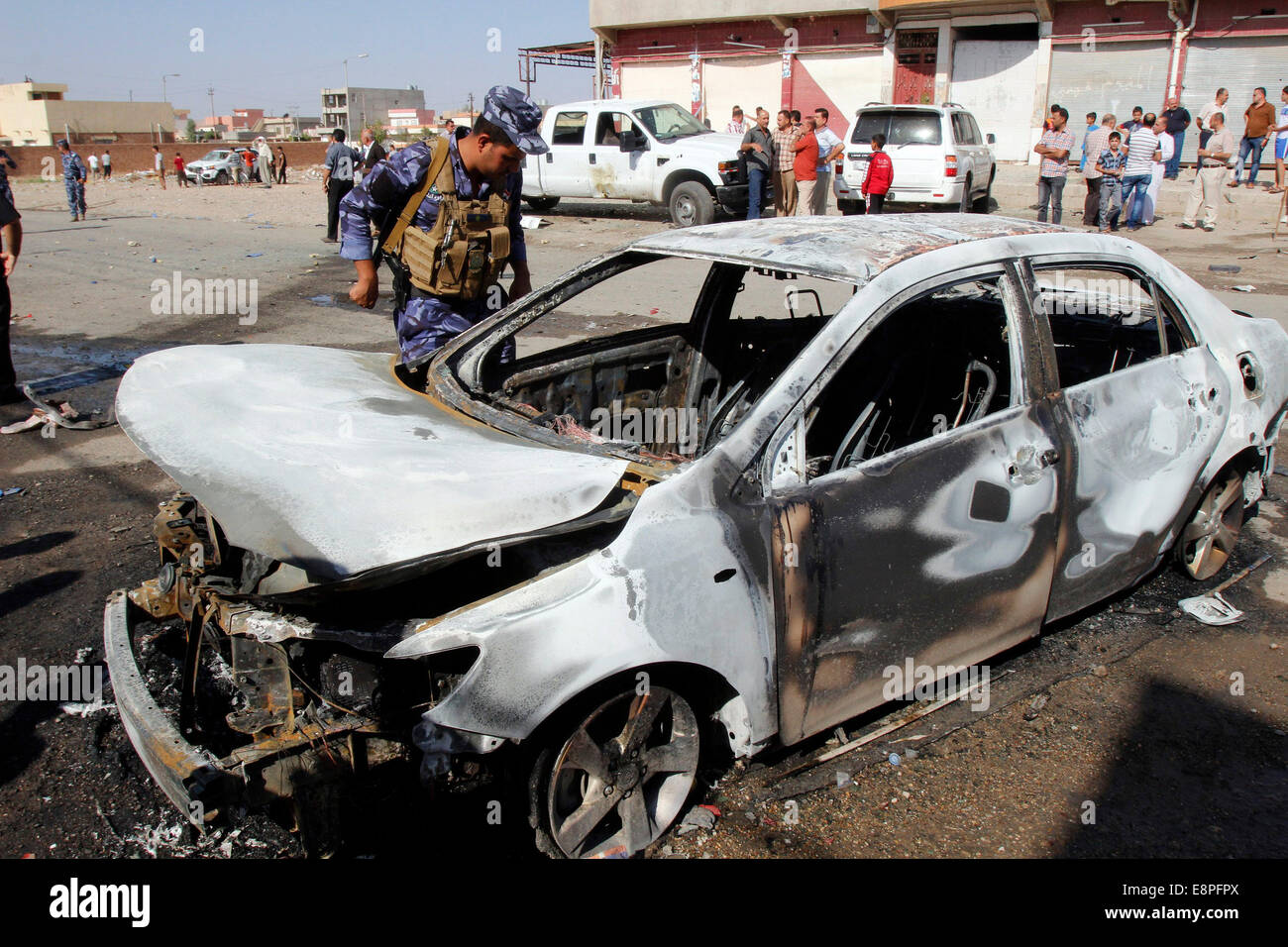 Kirkuk, Iraq. 13th Oct, 2014. A policeman inspects a car smashed at the ...