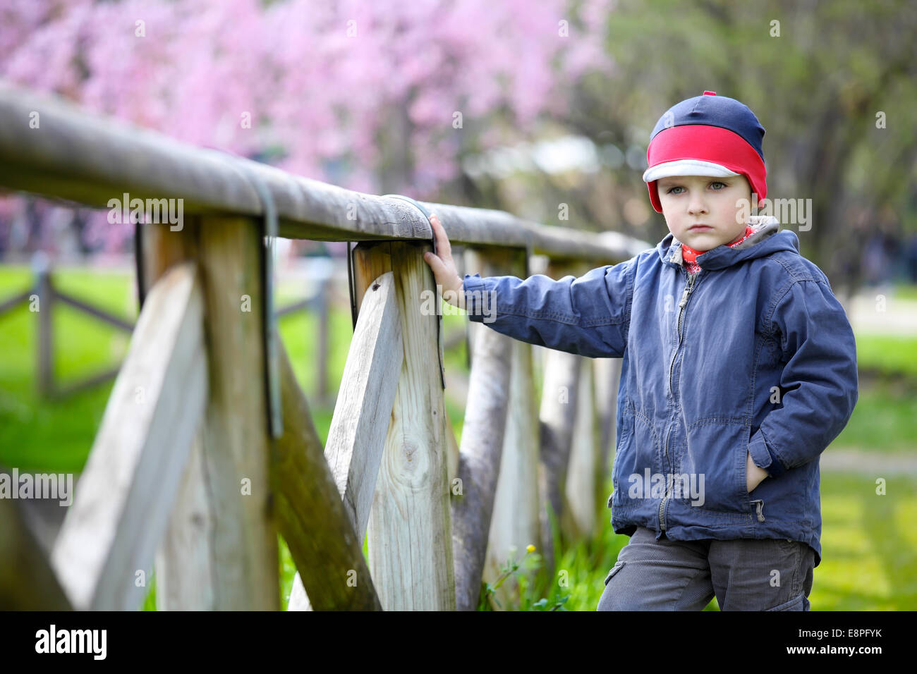 Portrait of a serious child outside in the park near a fence Stock ...