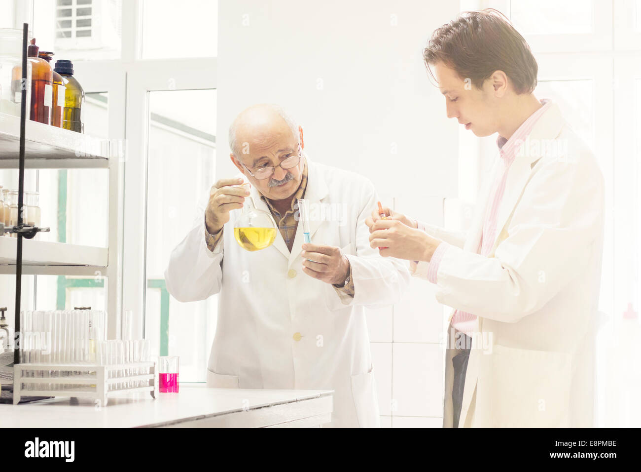 Scientist in a laboratory performing an experiment with his assistant ...