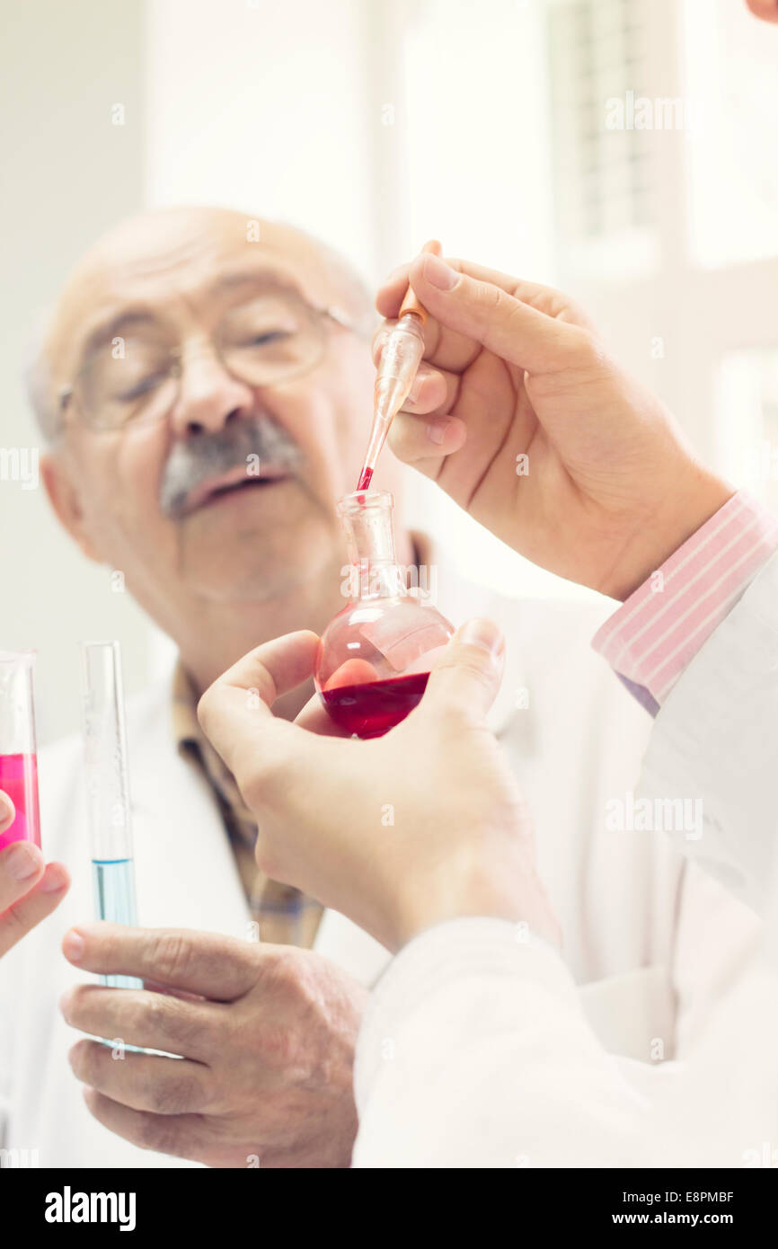 Scientist in a laboratory performing an experiment with his assistant ...
