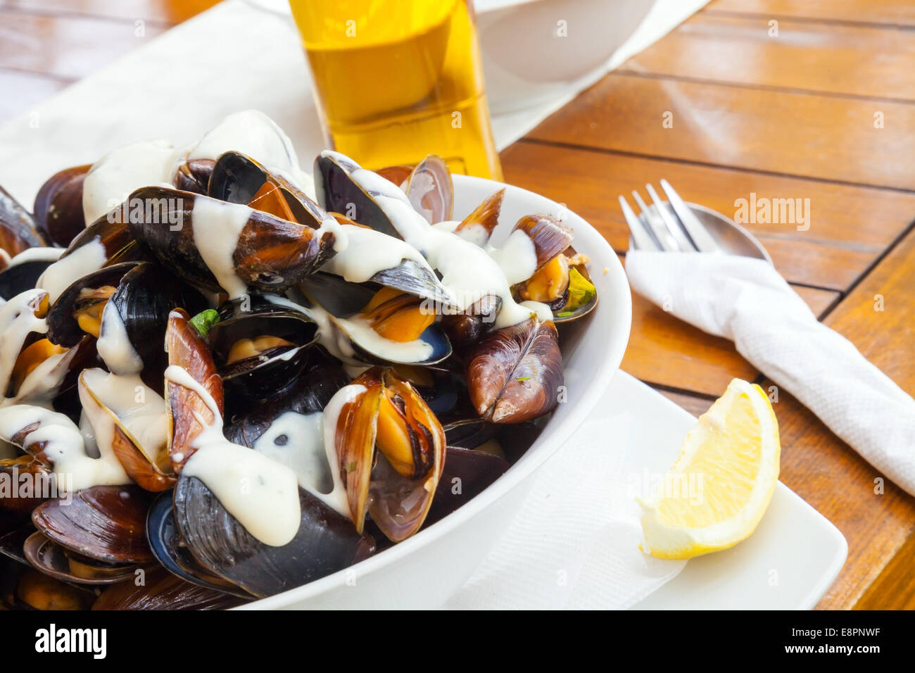 Plate full of mussels with garlic sauce on wooden table in restaurant ...