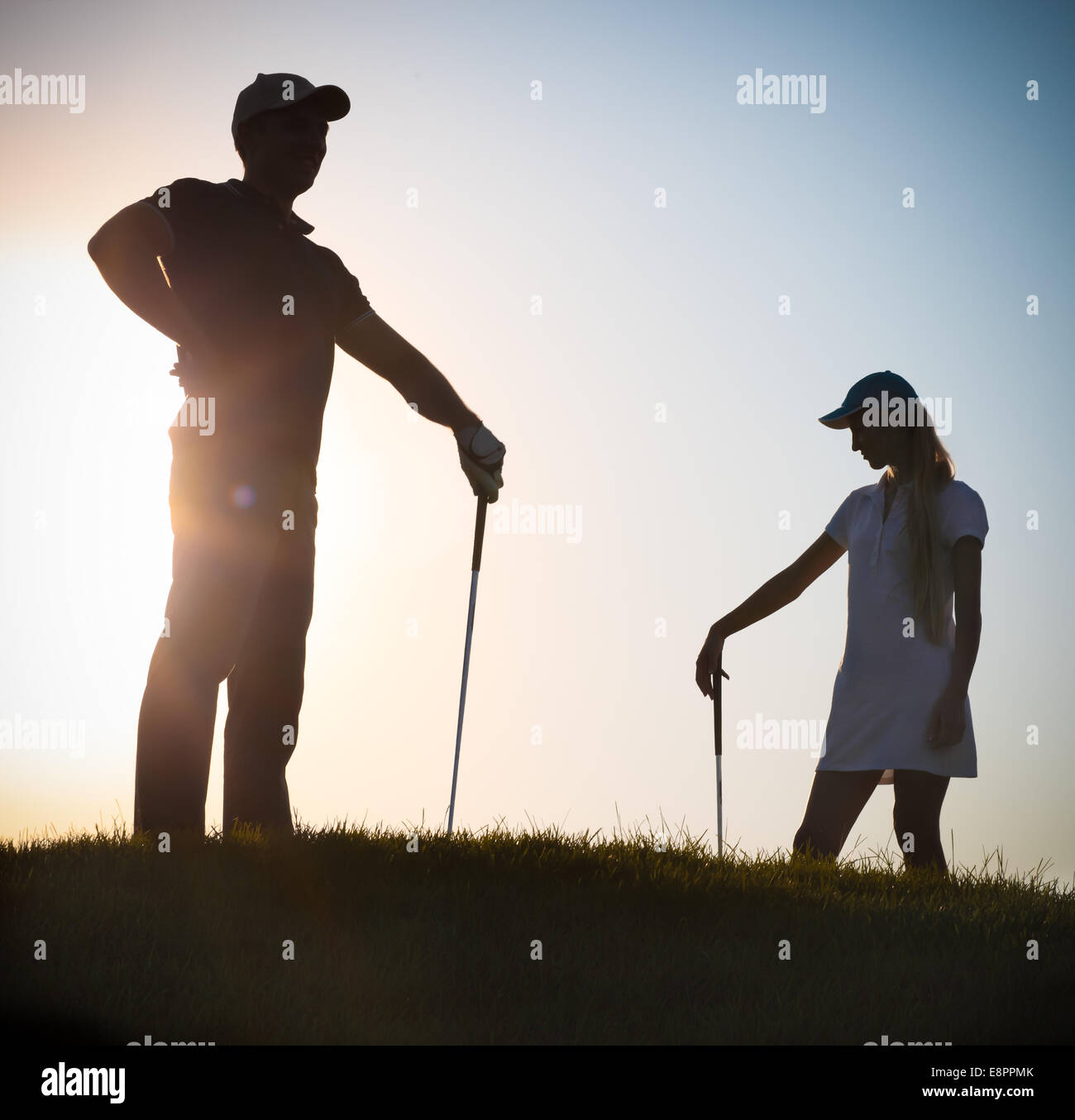 Male and female golfers playing golf at sunset Stock Photo - Alamy