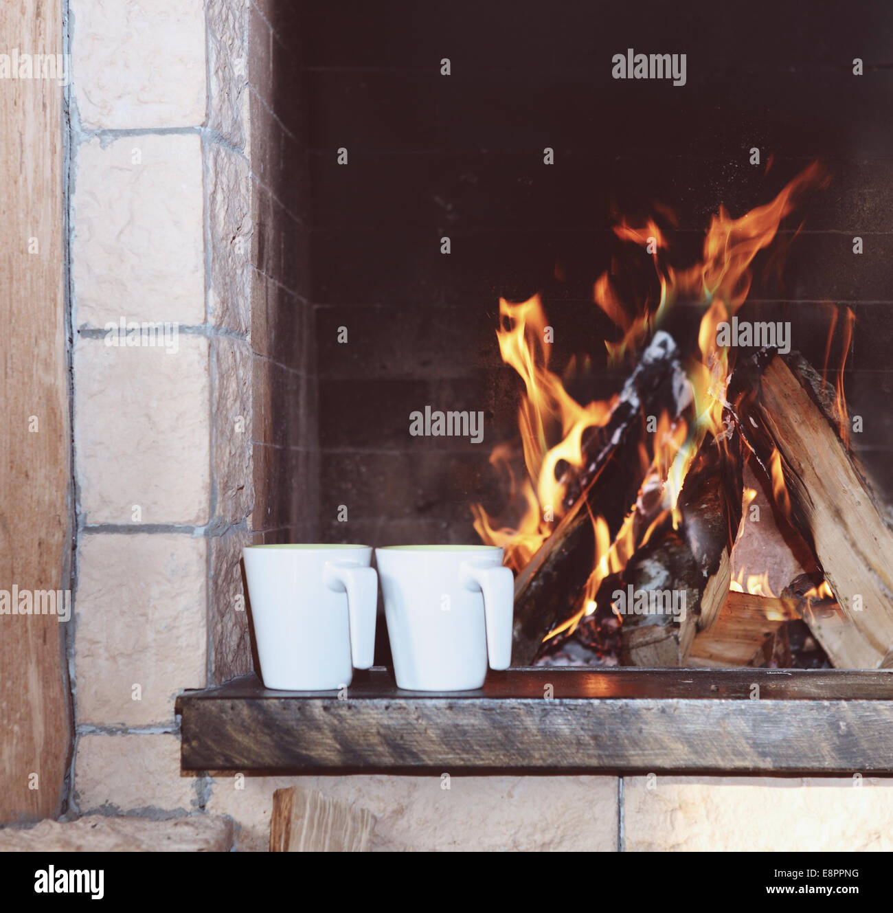 Two mugs near the fireplace with fire Stock Photo - Alamy