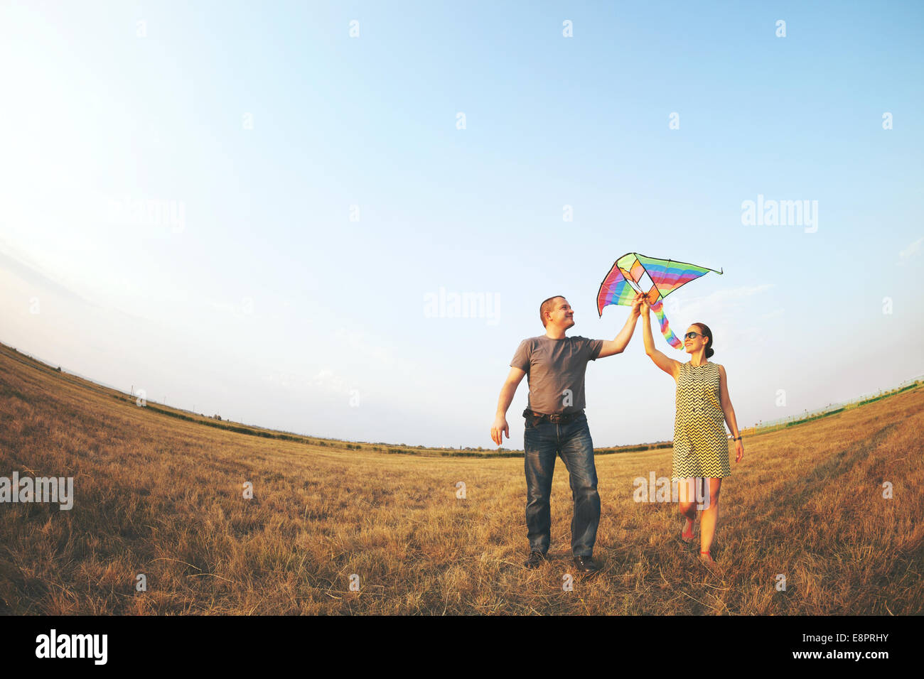 Happy young couple in love with flying a kite Stock Photo - Alamy