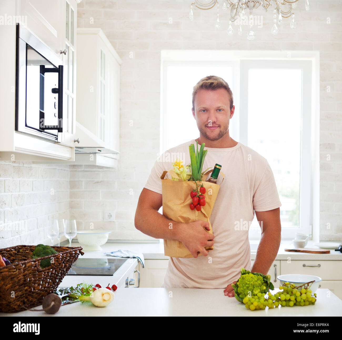 Man holding paper bag full of groceries on the kitchen background ...