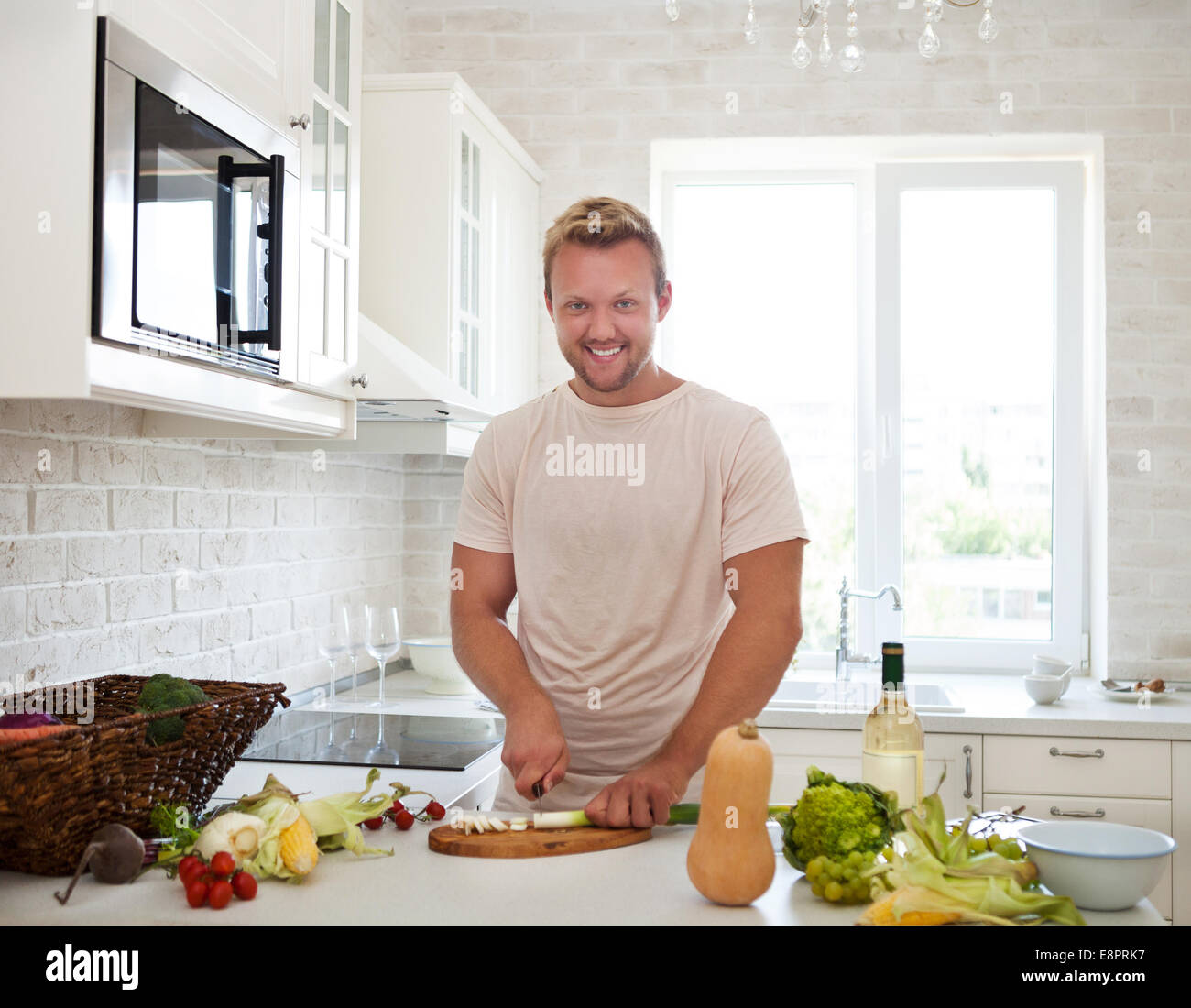 Handsome man cooking at home preparing salad in kitchen Stock Photo - Alamy