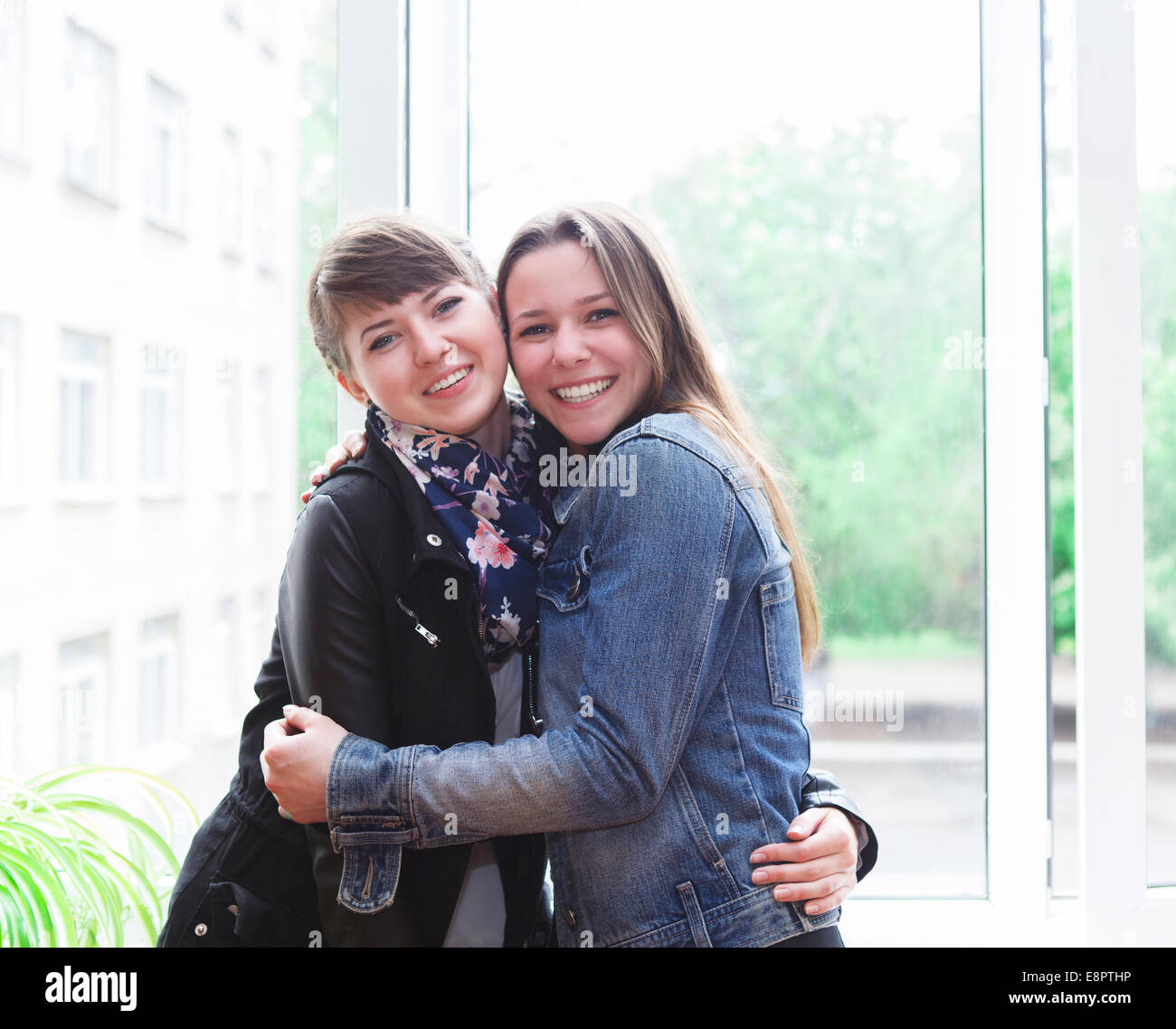 Two happy female students near the window in classroom Stock Photo - Alamy