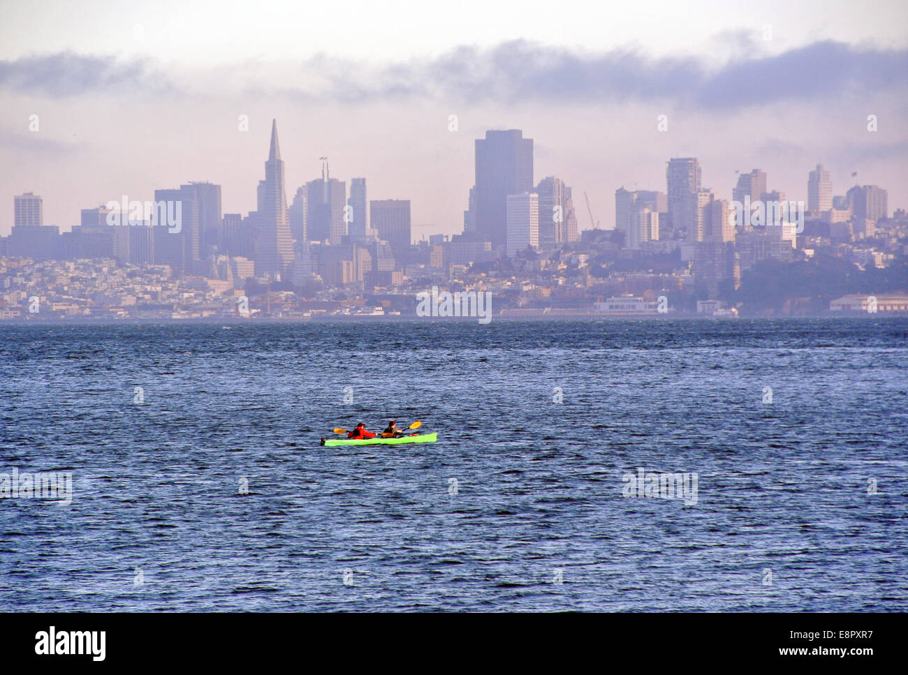 two women paddle kayak on san francisco Bay with skyline in background ...