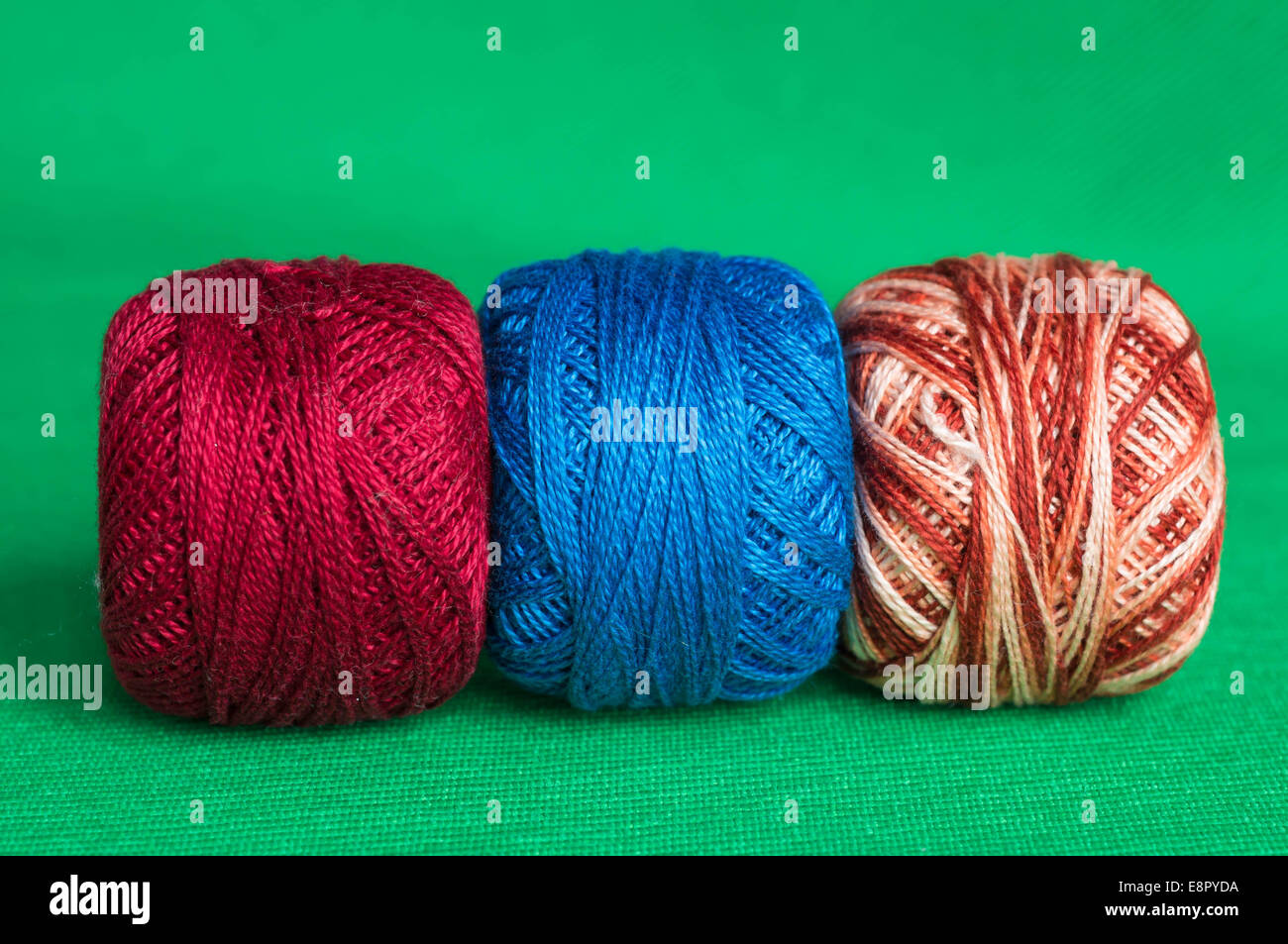 Three balls of a multi-colored yarn on a green background Stock Photo ...