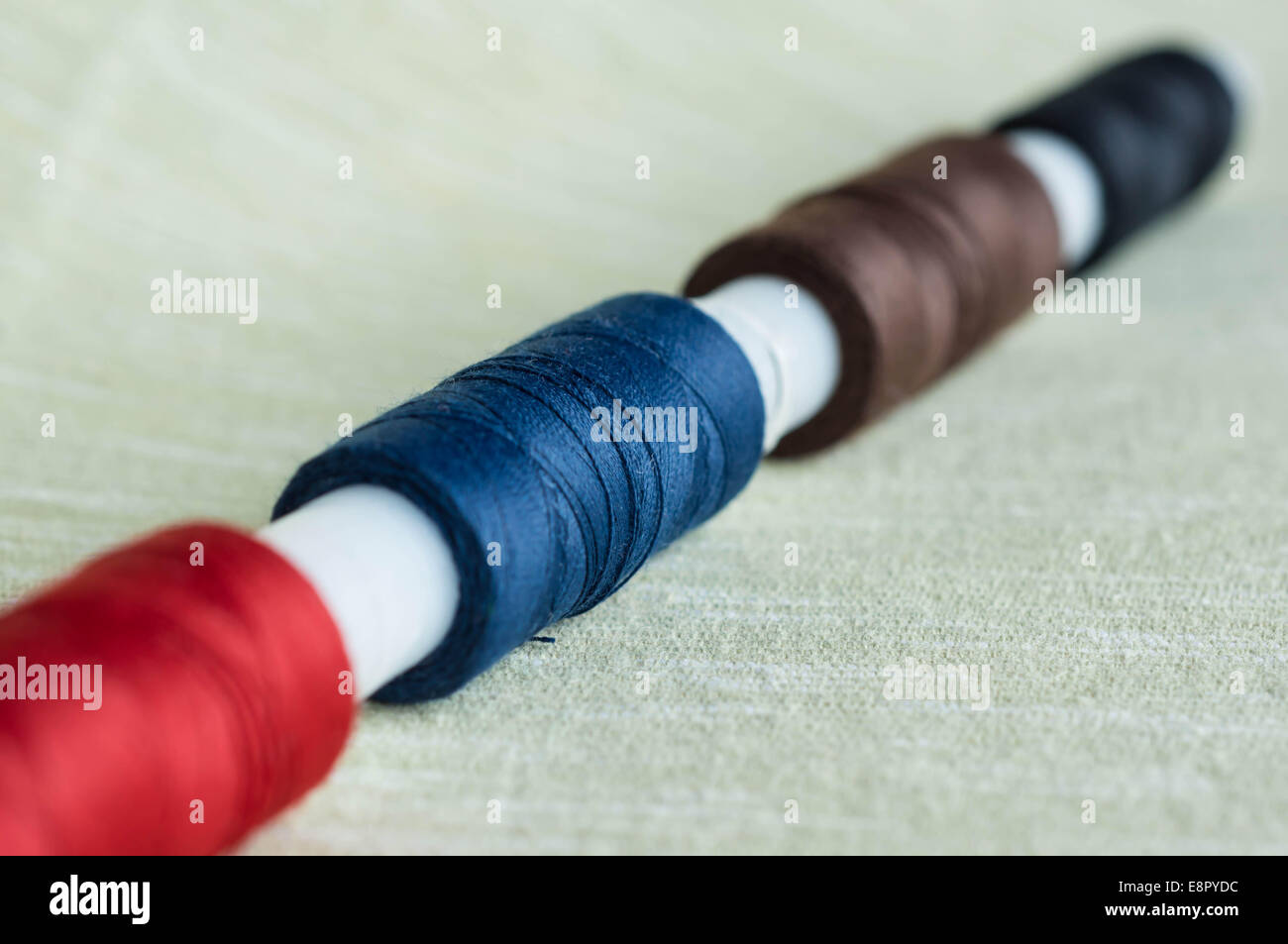 A row from coils of threads on a textile background Stock Photo - Alamy