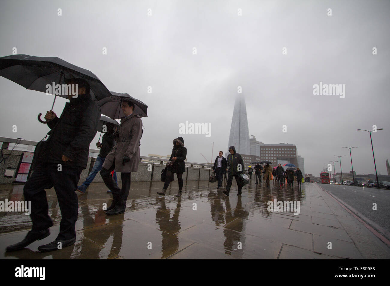 People walk over London Bridge with Shard in background in rain, fog ...