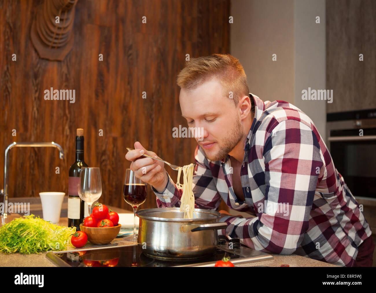 Handsome man cooking at home preparing pasta in a kitchen Stock Photo ...