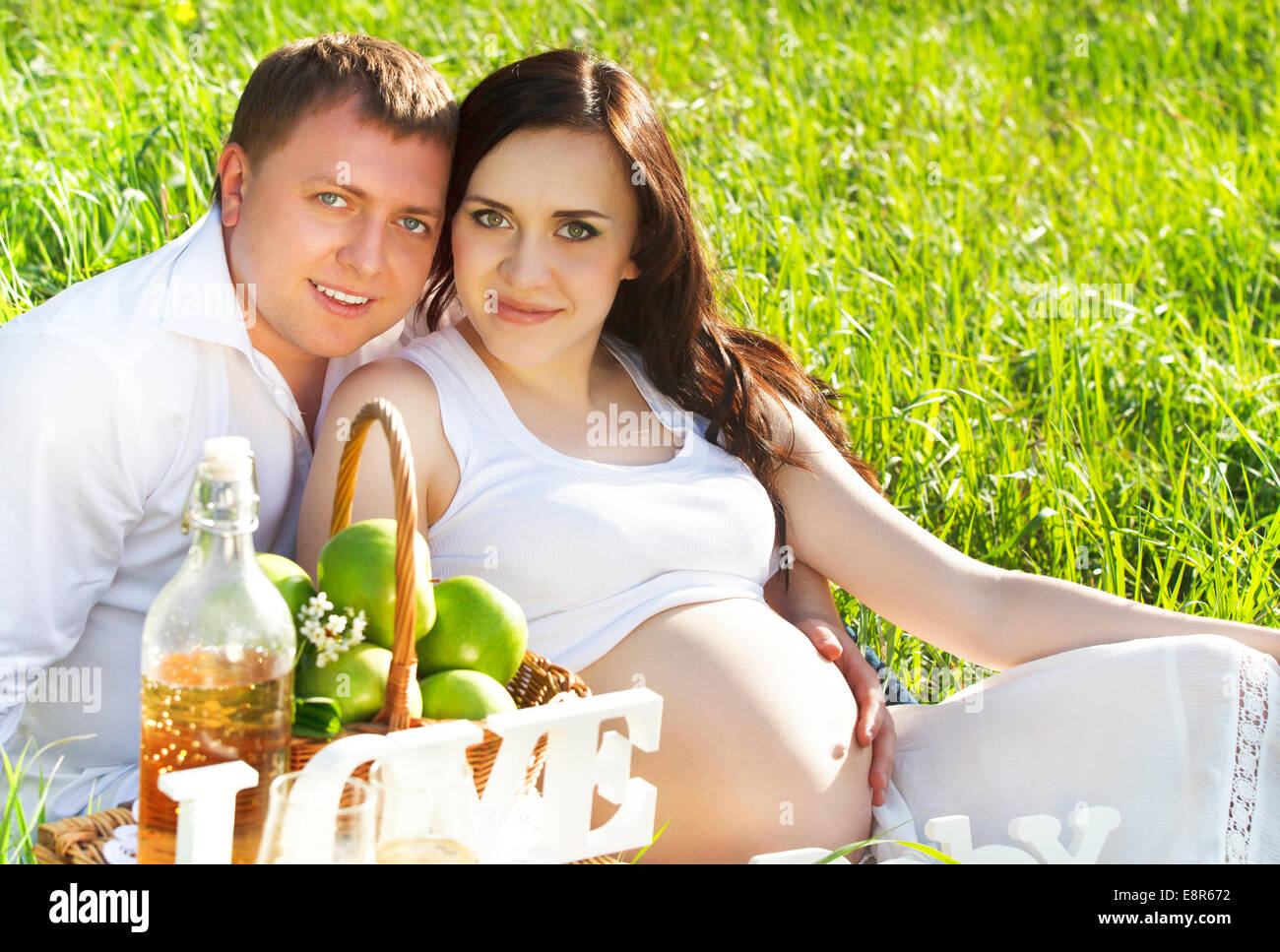 Young happy pregnant couple in the flowering spring park. Outdoors ...