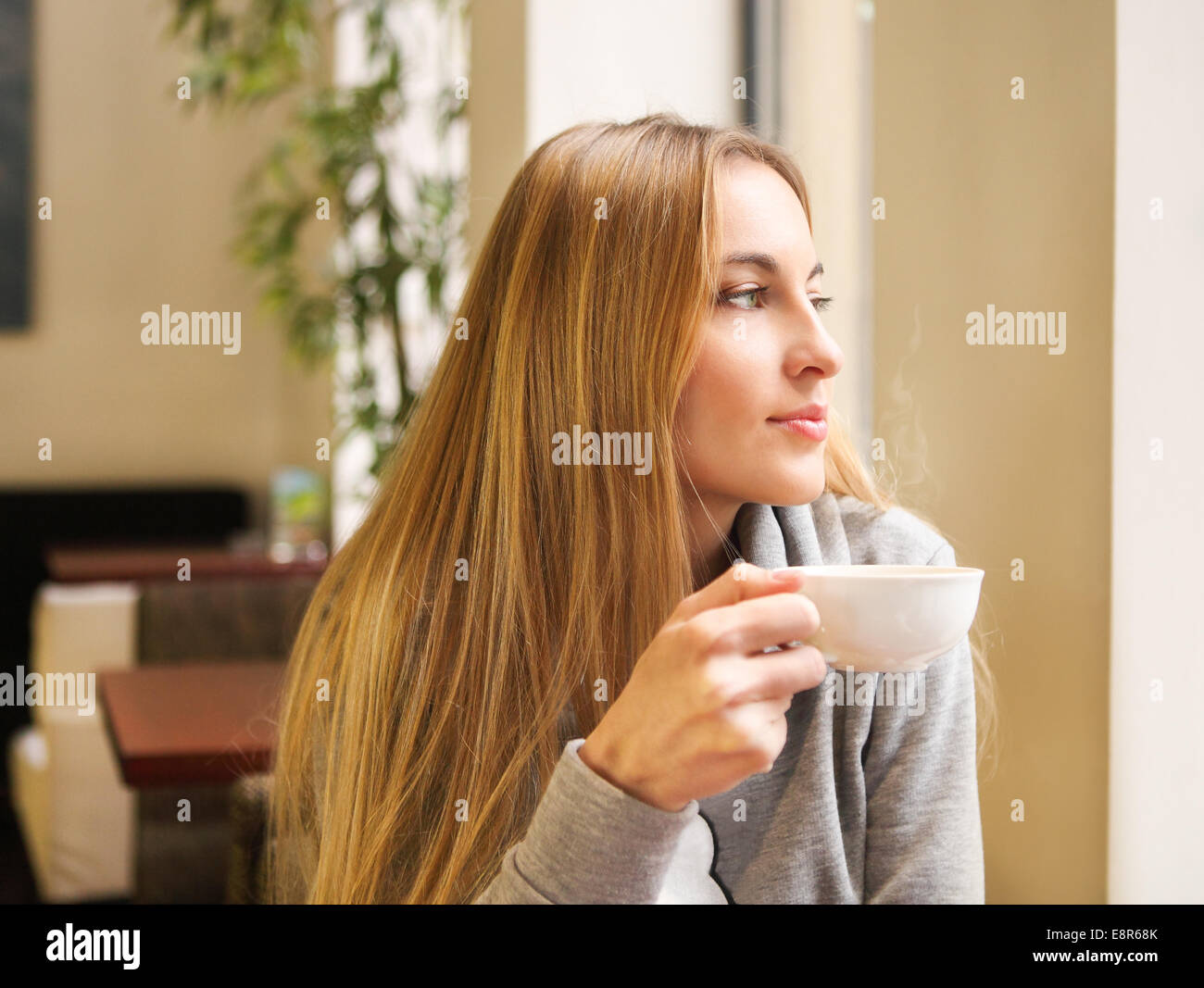 Smiling blond woman drinking tea in cafe Stock Photo - Alamy