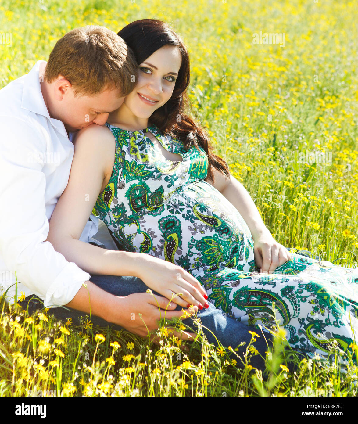 Young happy pregnant couple in the flowering spring park. Outdoors ...