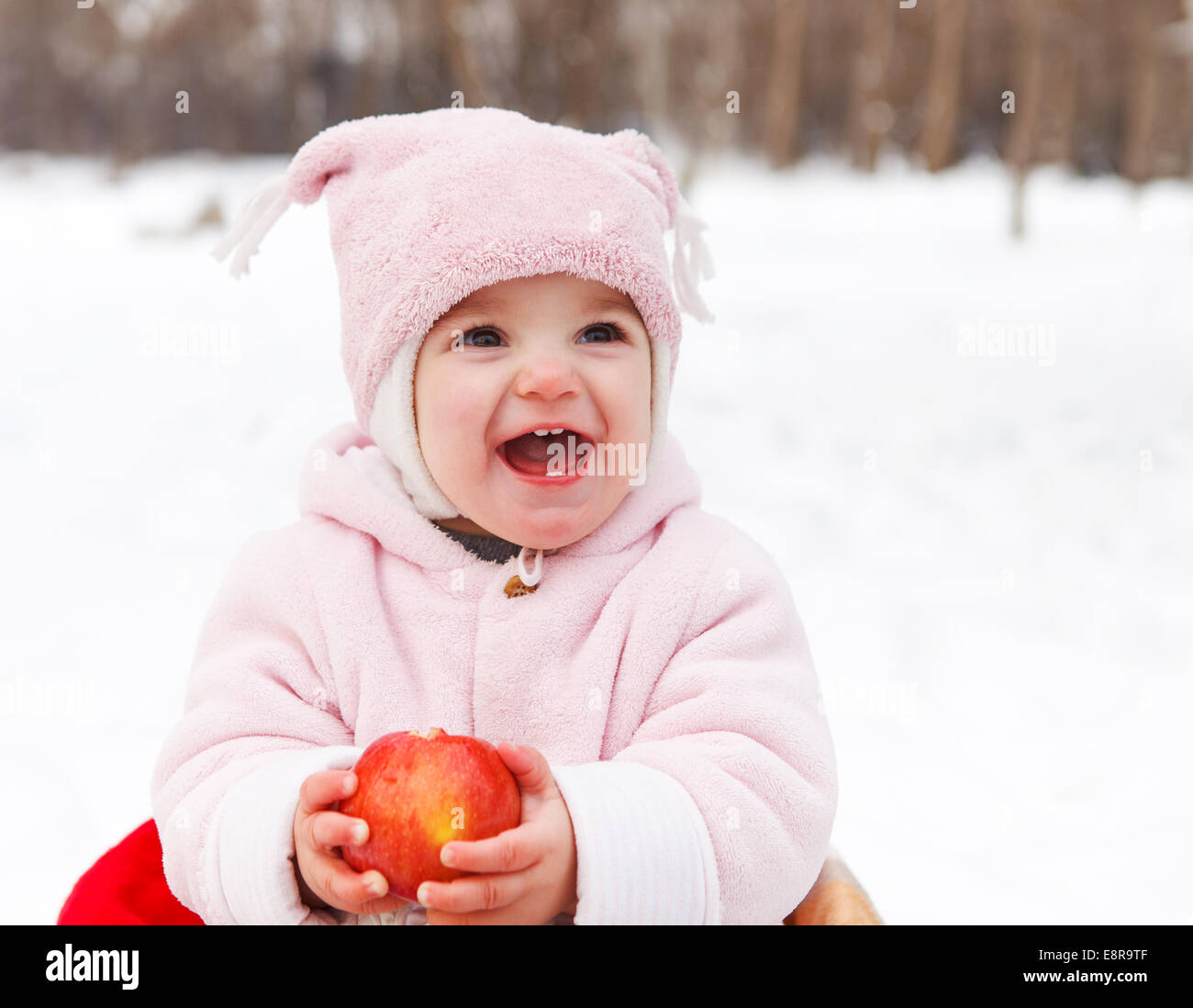 Happy smiling baby with apple in winter park Stock Photo - Alamy