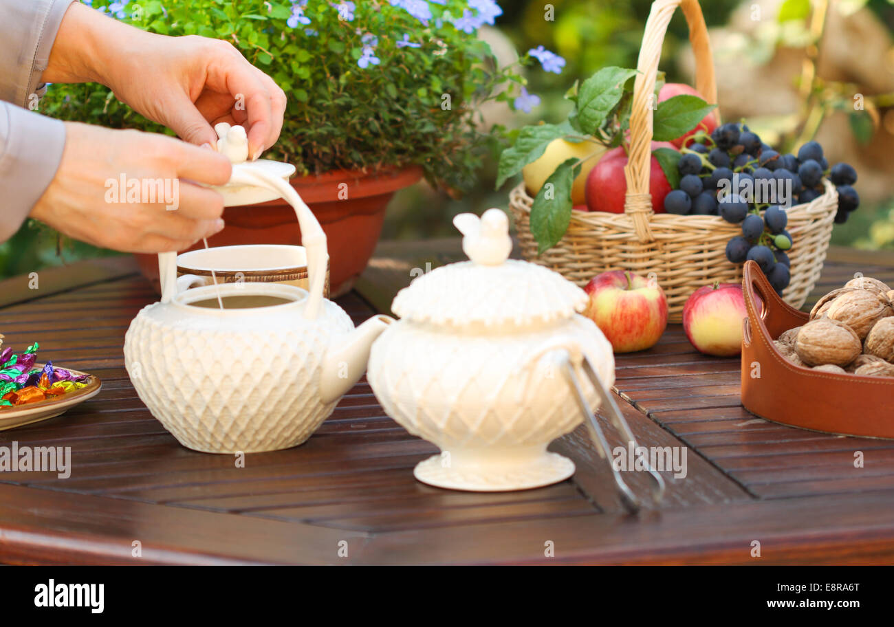 Hands of woman preparing tea in teapot in a garden outdoors Stock Photo ...