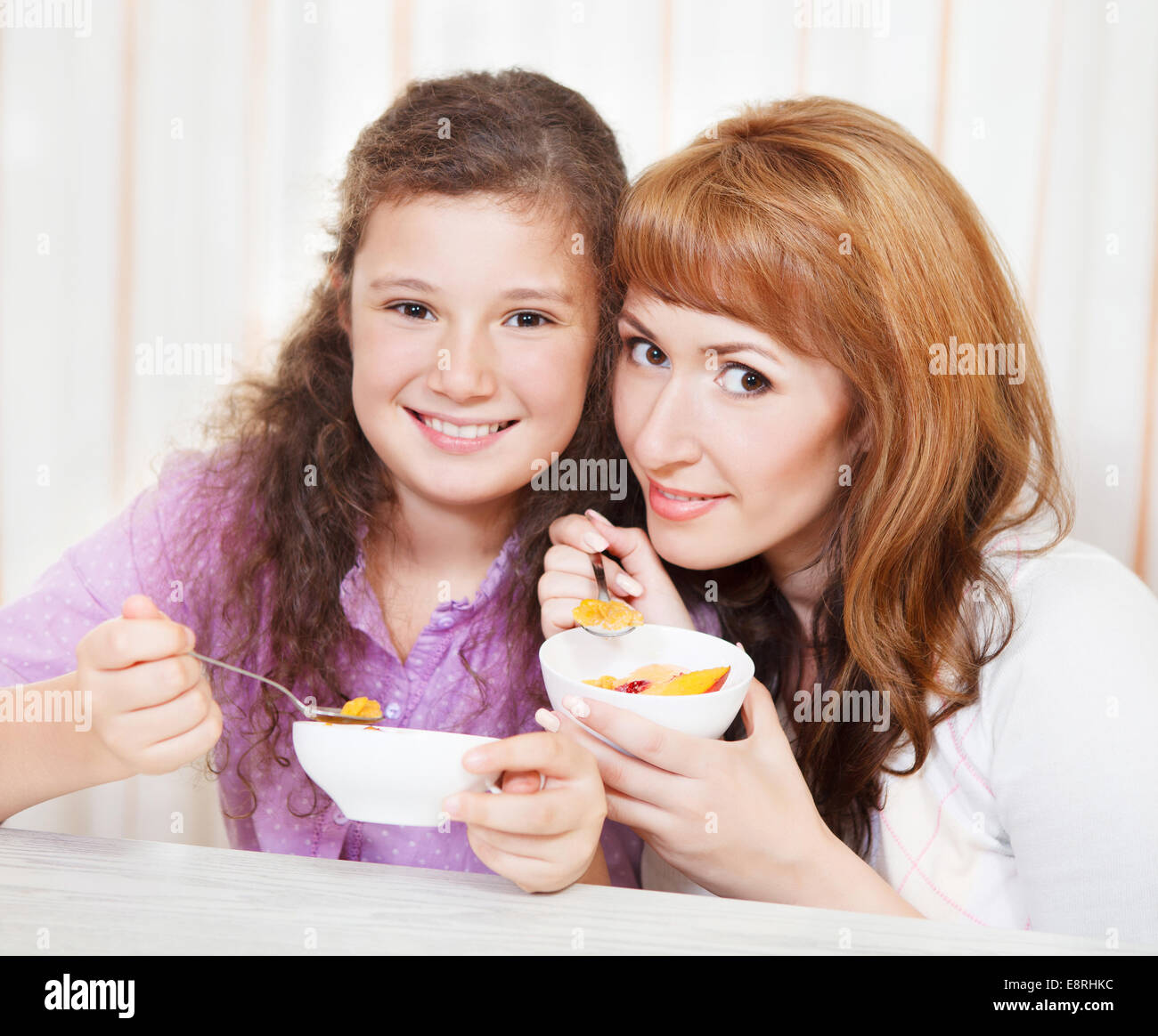 Happy mother and daughter eating cereal and fruit Stock Photo - Alamy