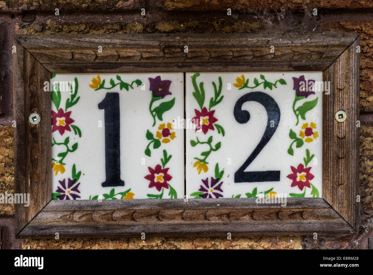 The painted flowers and leaves surround the number twelve all in a wood ...