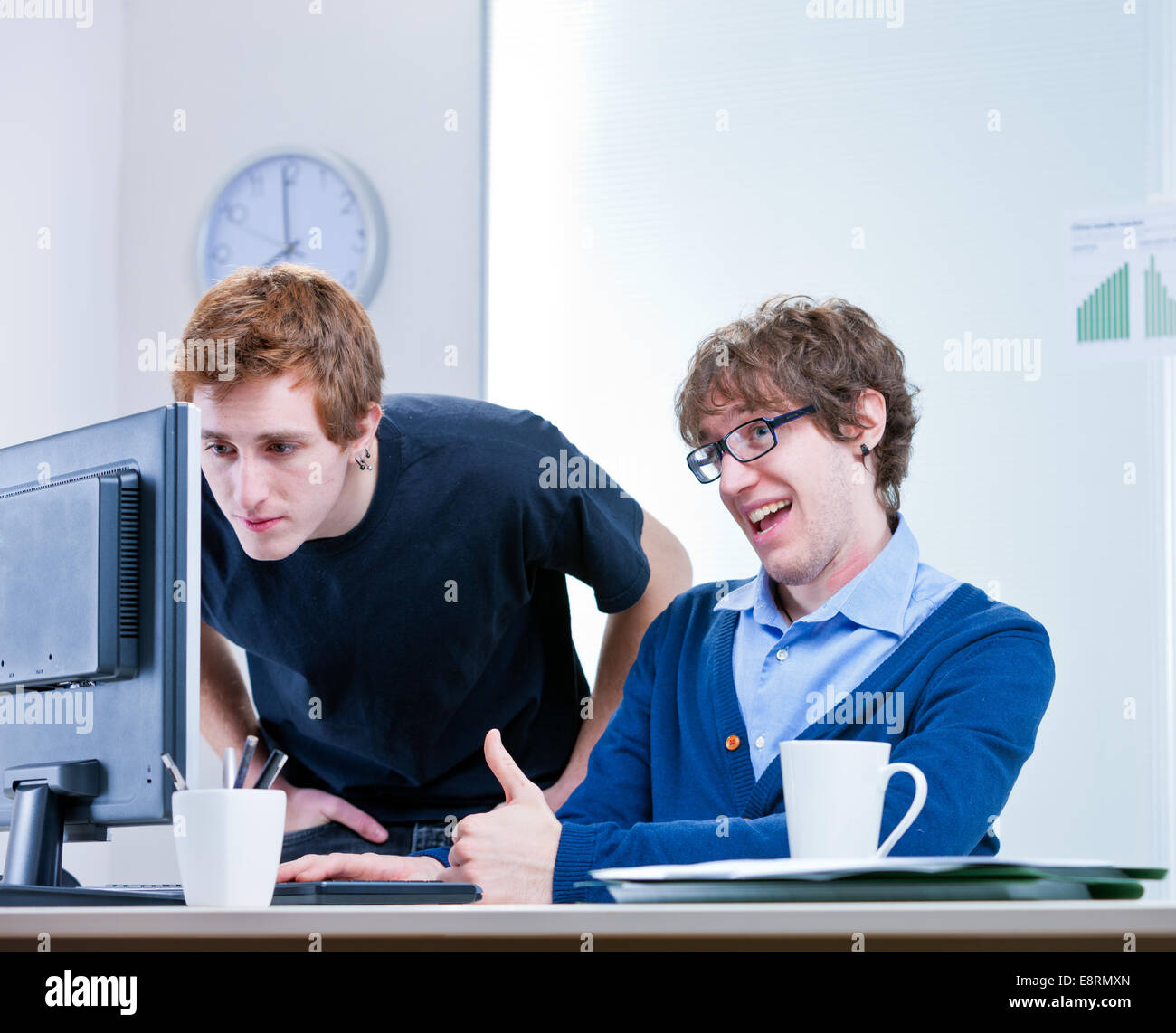 a couple of young employees in an office working together to achieve ...