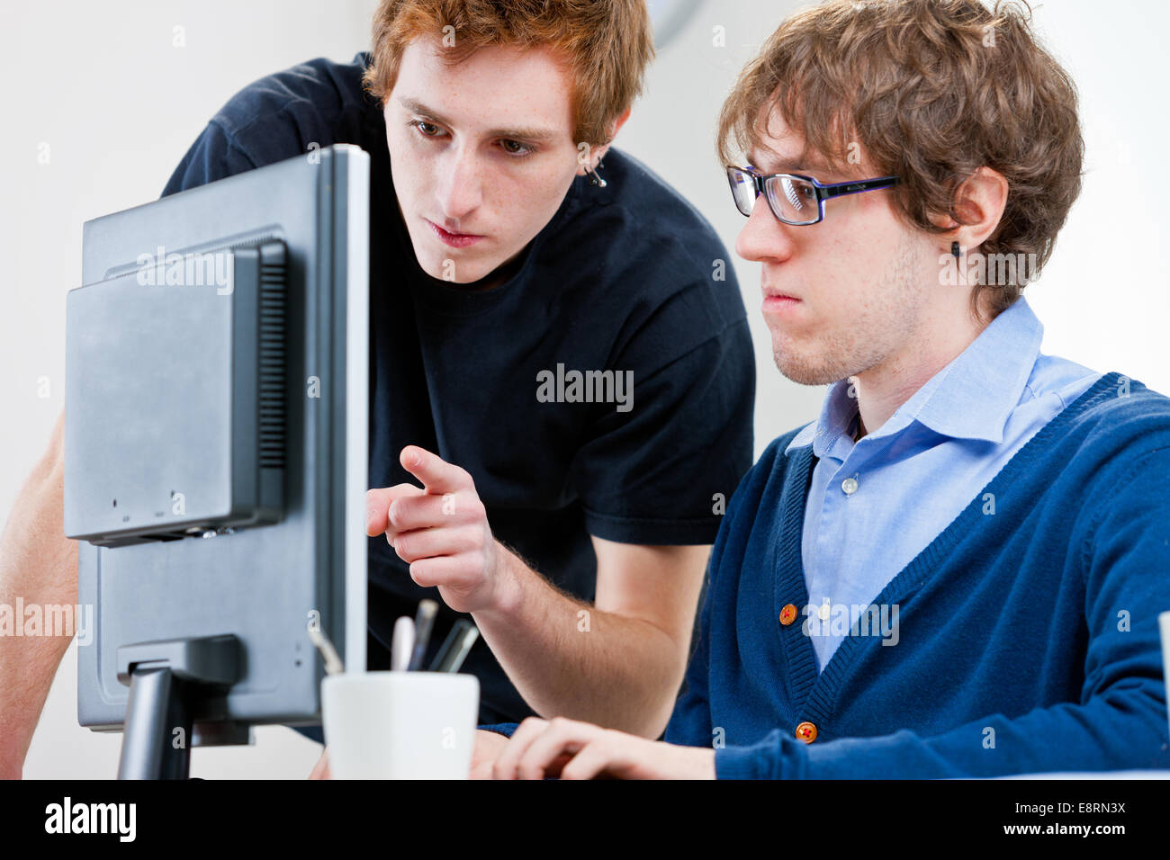 a couple of young employees in an office working together to achieve ...