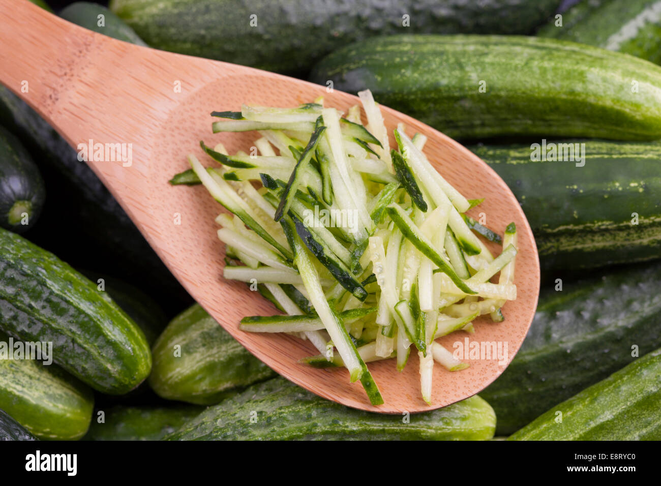 Chopped cucumber in a wooden spoon on cucumber background Stock Photo ...