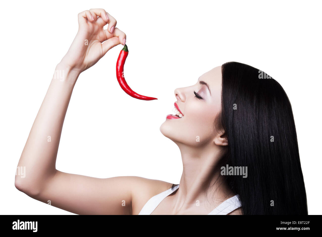 brunette woman eating chili pepper on white background Stock Photo - Alamy