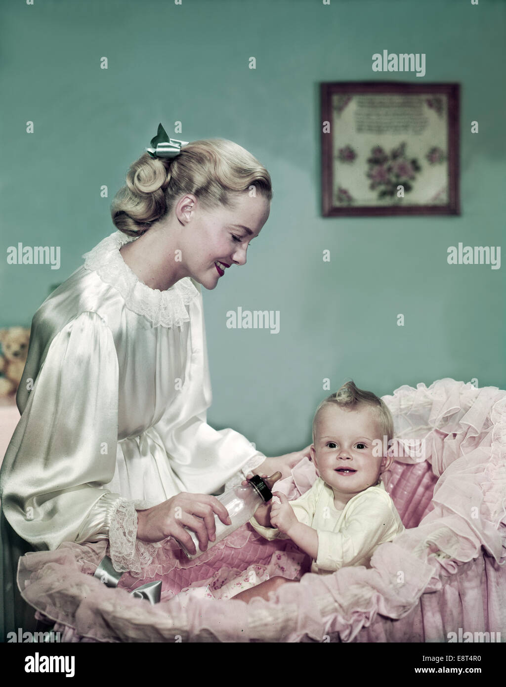 1940s 1950s SMILING WOMAN MOTHER FEEDING BABY BOTTLE IN BASSINET Stock ...