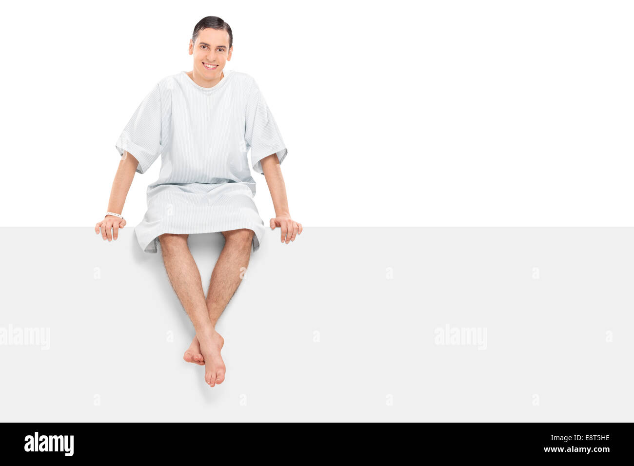 Cheerful male patient sitting on a blank panel isolated on white ...