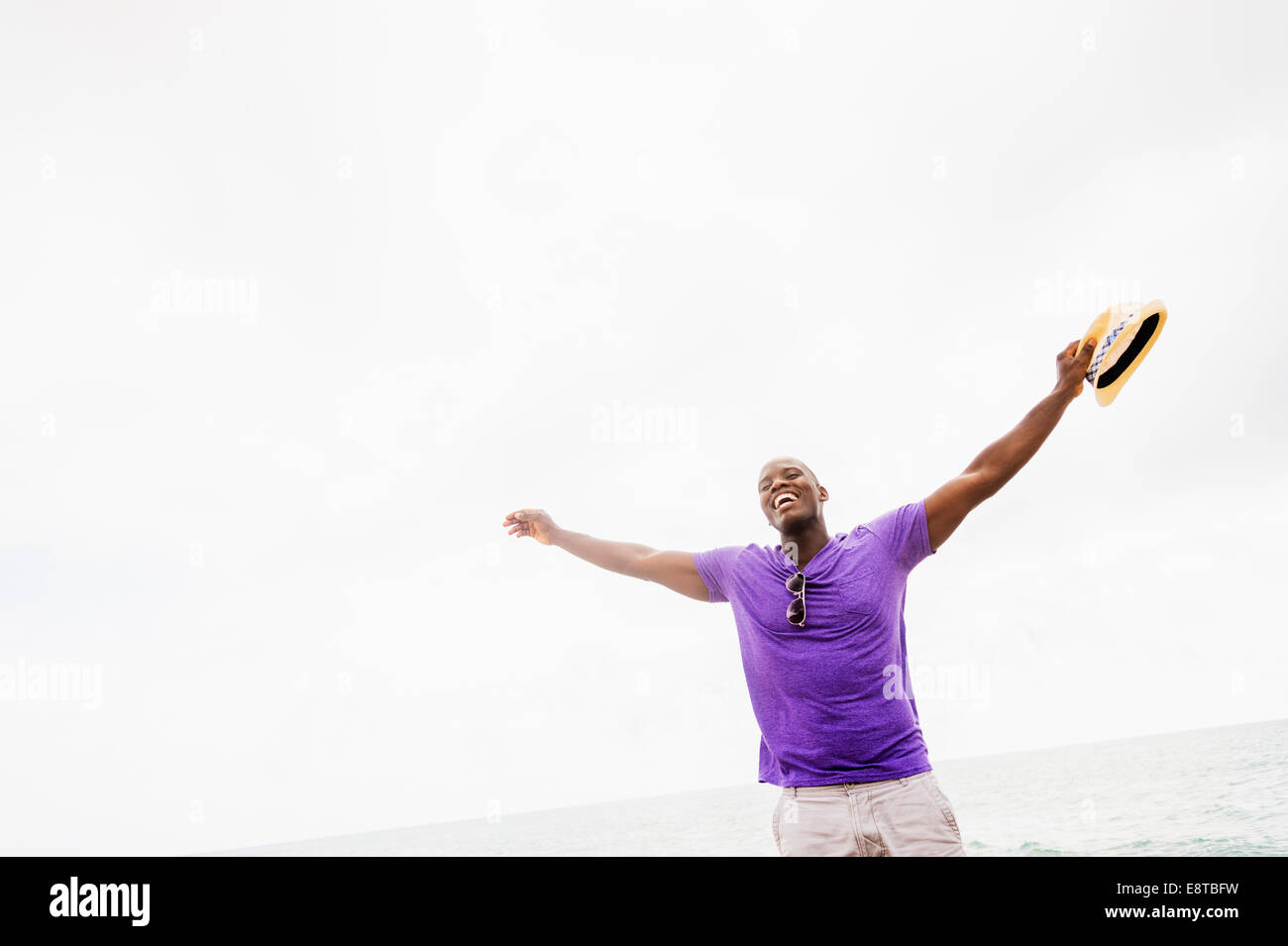 Mixed race man with arms outstretched on beach Stock Photo - Alamy
