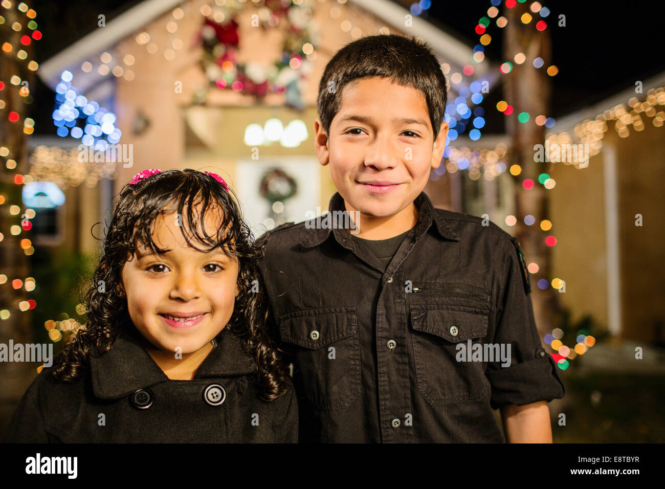 Hispanic brother and sister smiling outside house decorated with string ...