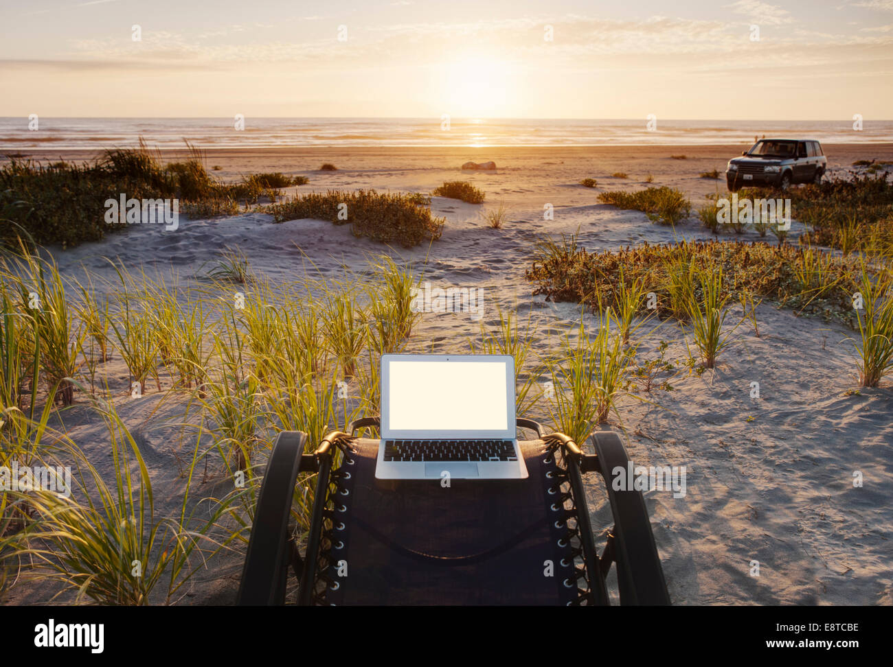 Laptop on deck chair overlooking sunset on beach Stock Photo - Alamy