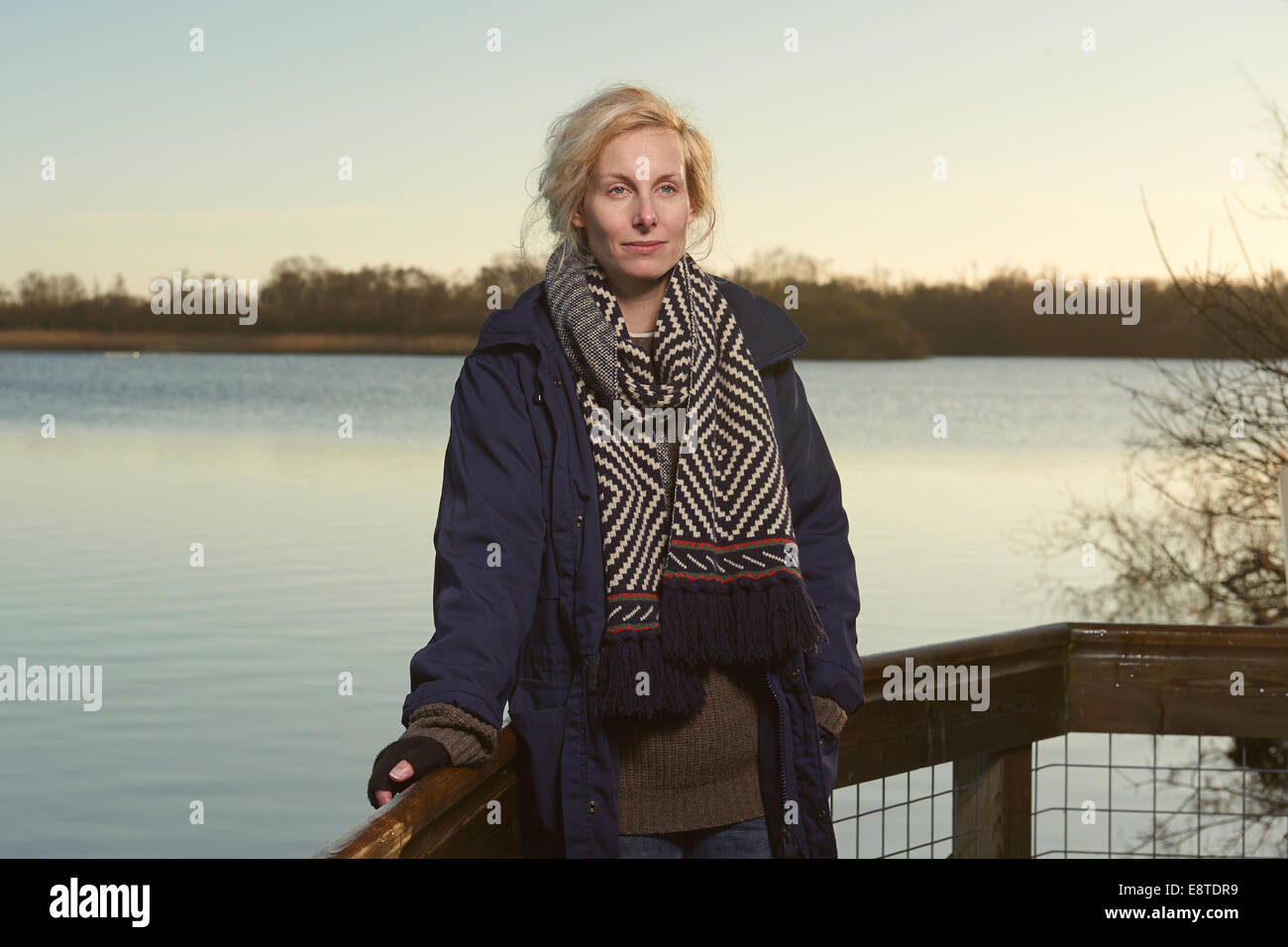 A woman in her 30's in winter clothes in front of a lake in the Norfolk ...