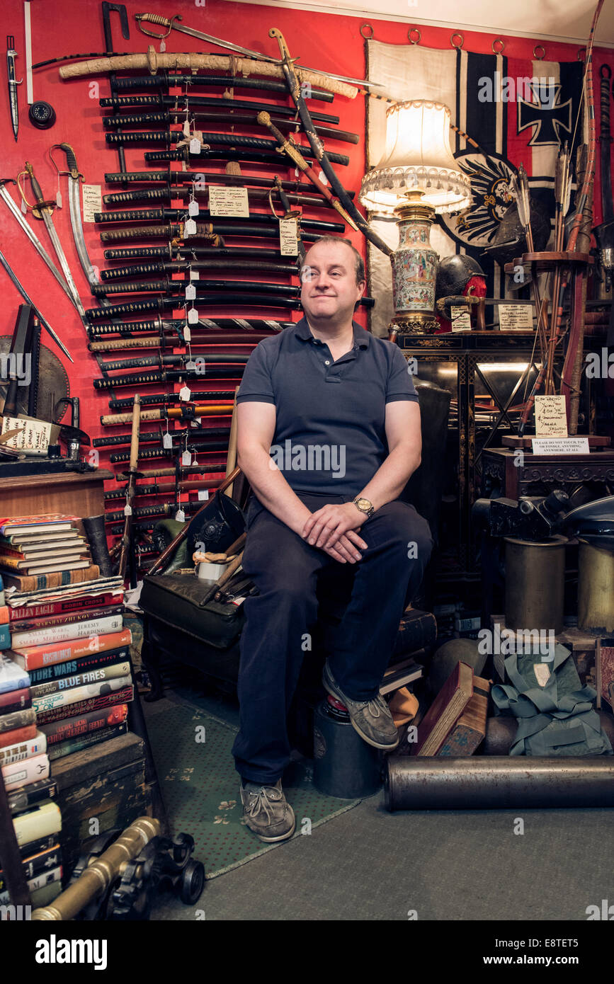A male shopkeeper stands in his historical military antique shop ...