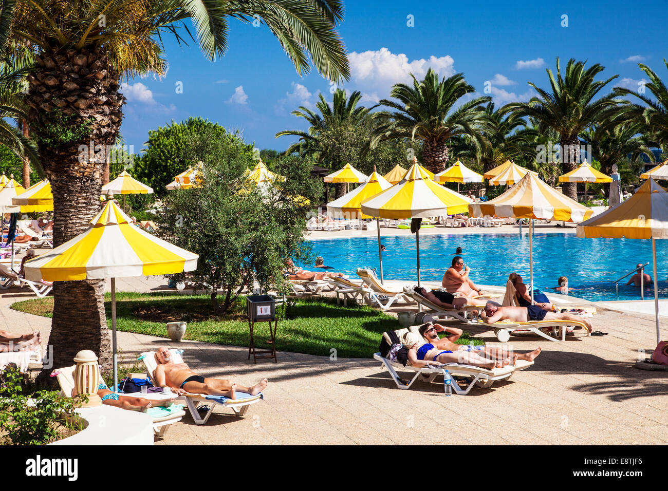Holidaymakers sunbathing around the poolside area of a five star resort ...