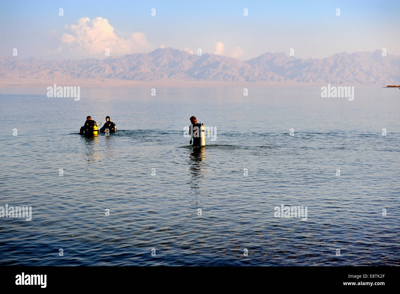 Three scuba divers standing in shallow water off beach Stock Photo - Alamy