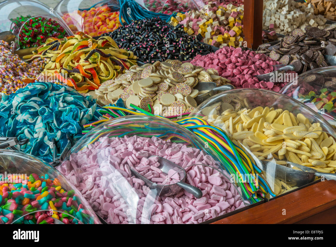 Selection of multi-colored candy sweets and metal serving scoops laid ...