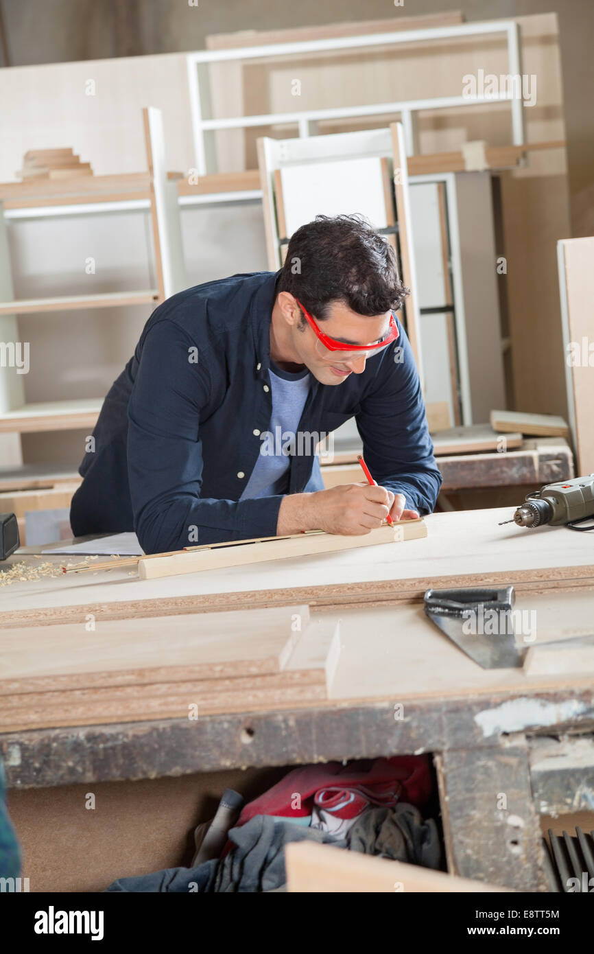 Carpenter Measuring Wood At Workbench Stock Photo - Alamy