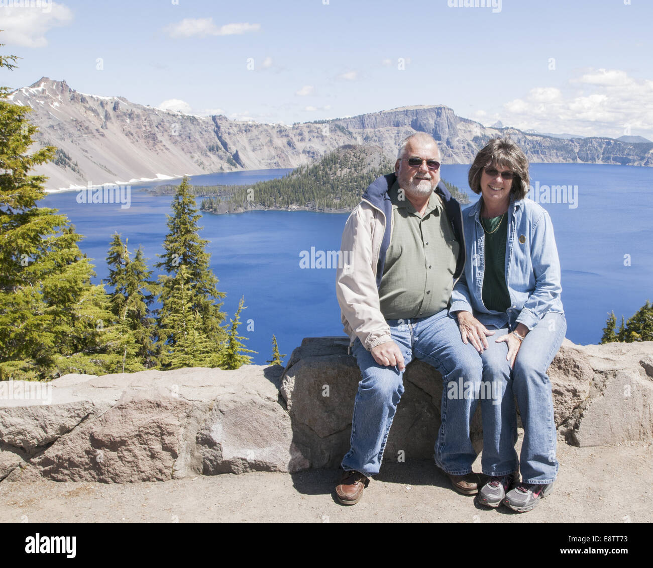 Couple sitting on ledge at Crater Lake, Oregon Stock Photo - Alamy